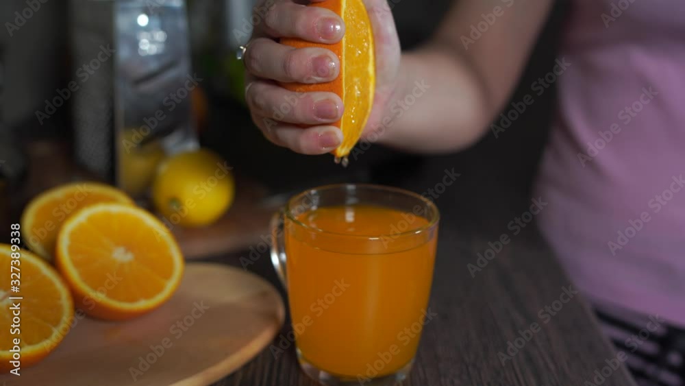 A girl squeezes an orange in the kitchen to get freshly squeezed orange ...