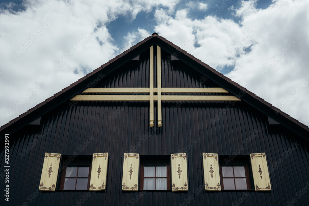 Gable roof of cottage with cloudy sky in background.There are 3 glass ...