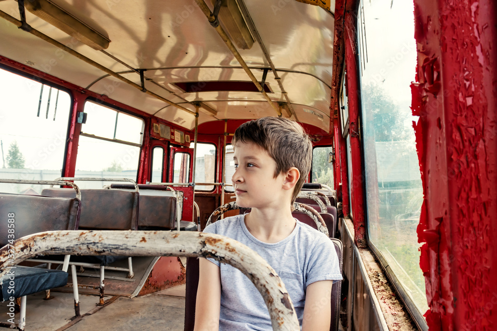 A 10 years boy riding in a old vintage bus, he is sad because his poor ...