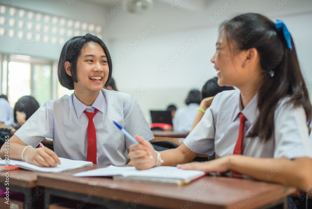 A pretty smiling Asian female student in white uniform is turning her ...