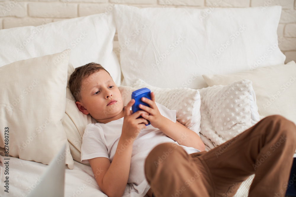Focused boy is lying on a bed and playing a PSP video game. Stock Photo ...
