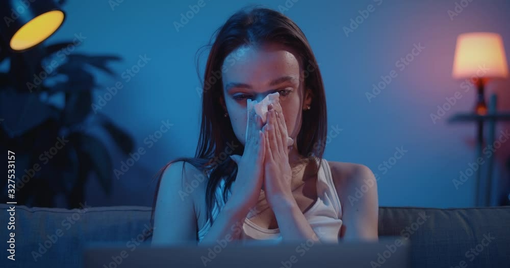 Sad young woman worrying while watching an emotional scene in movie ...