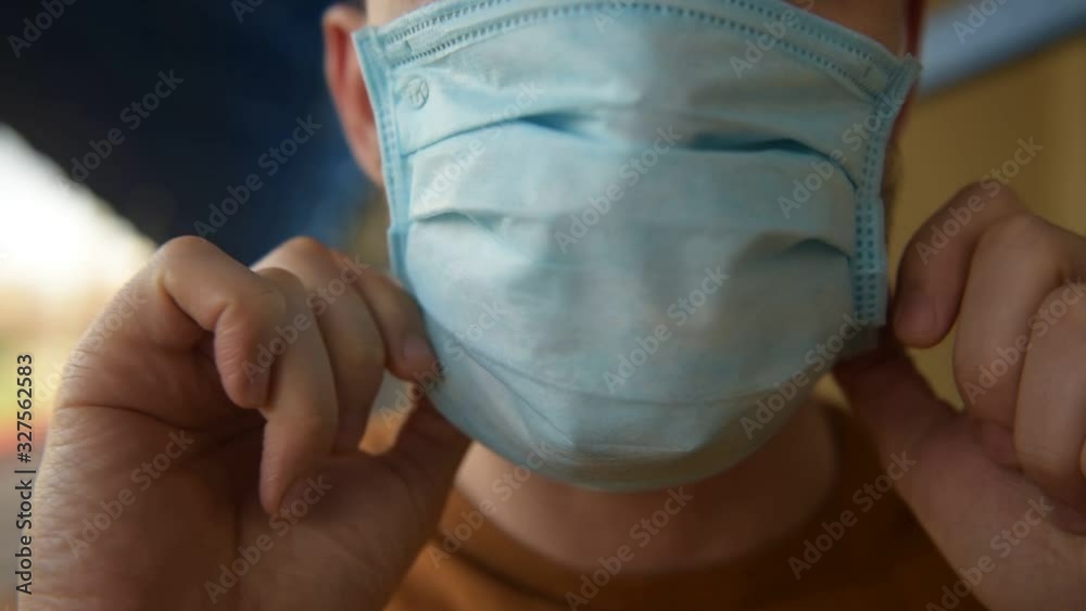 Man in surgical mask standing on empty stadium. Man puts the mask on of ...