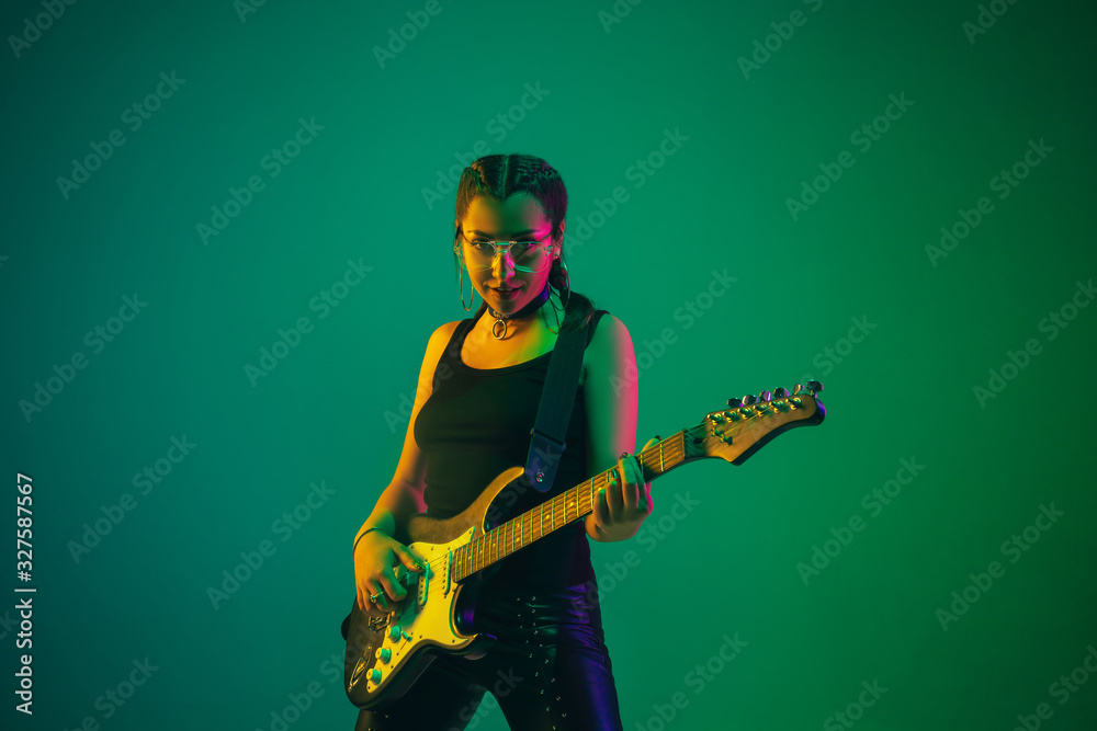 Rockstar. Caucasian female guitarist portrait on green studio ...