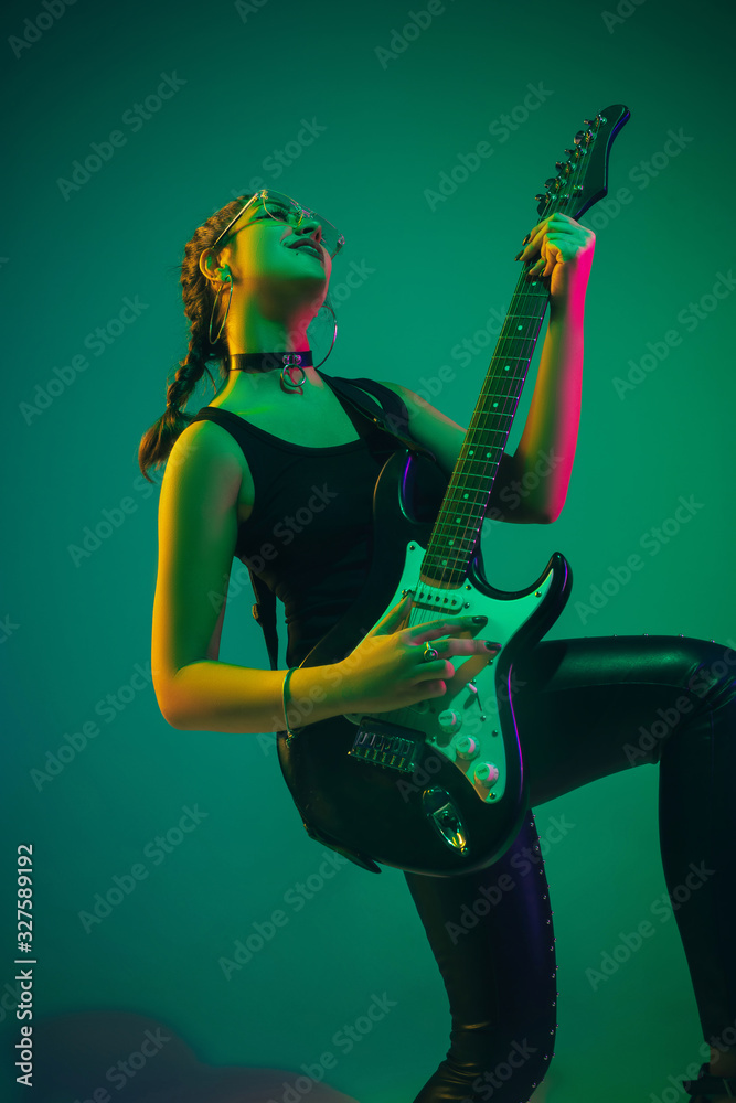 Rockstar. Caucasian female guitarist portrait on green studio ...