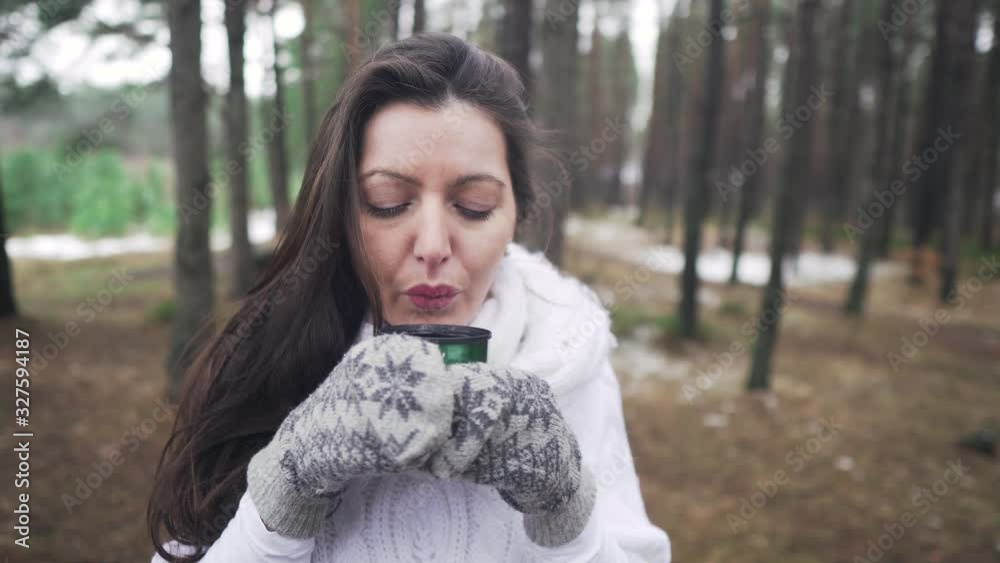 Woman drinking tea in the forest. The girl drinks tea from a thermos ...