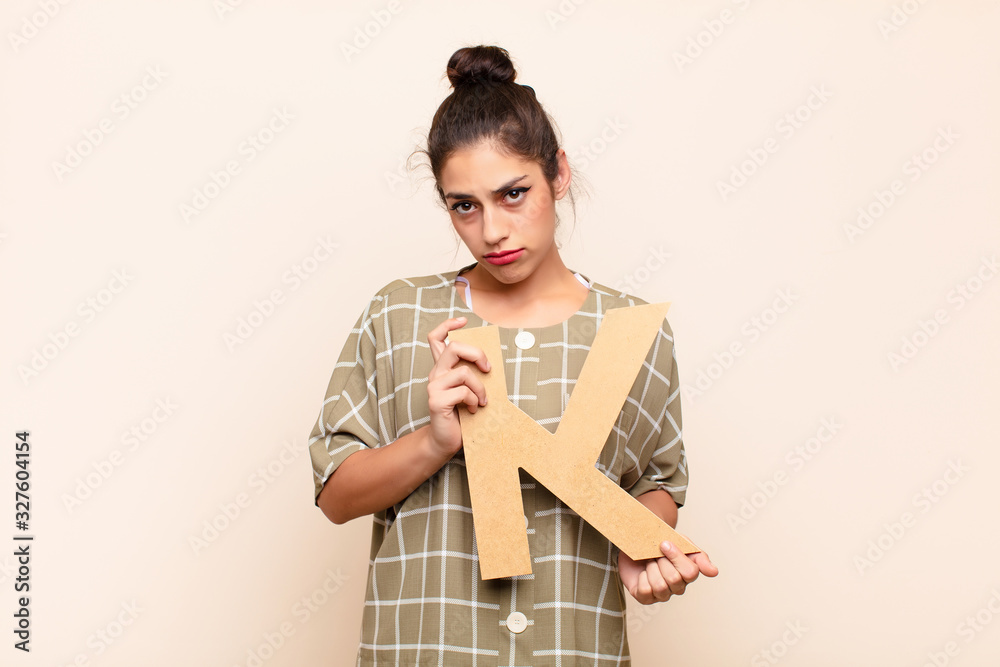 young pretty woman sad, depressed, unhappy, holding the letter K of the ...