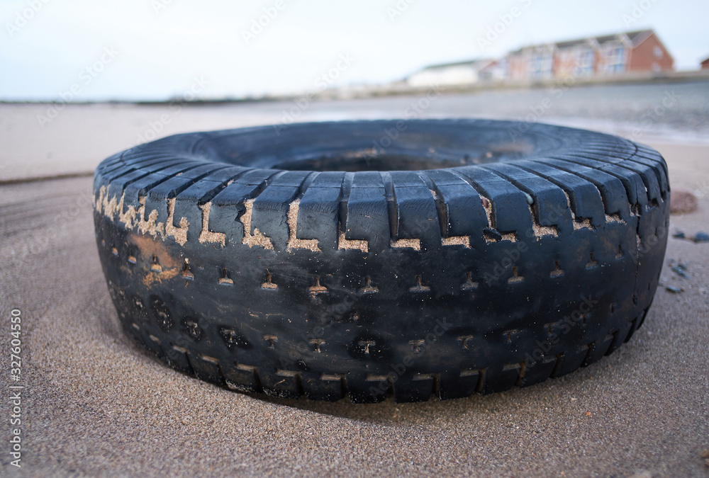 rubber dirty old vehicle tyre washed up on a sandy luxurious beach ...
