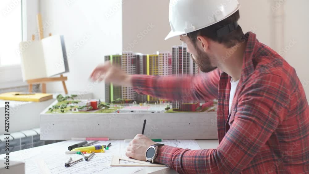 Young caucasian architect studying a floor plan, a serious civil ...