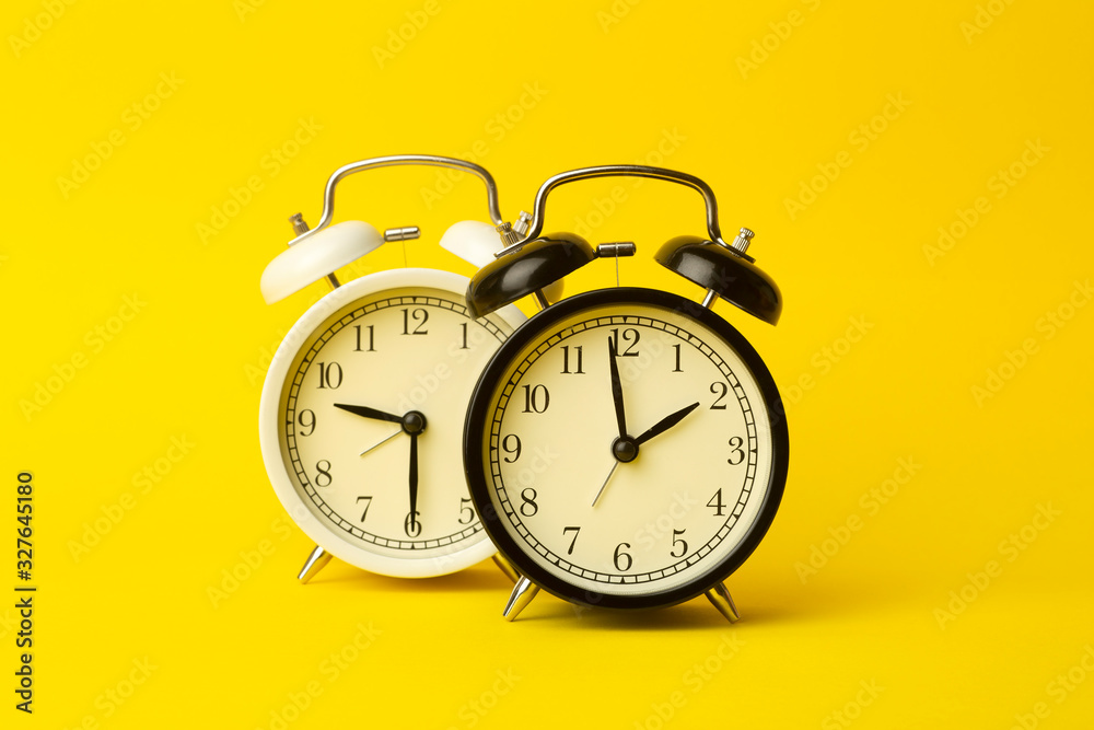 Time background concept. Vintage classic alarm clock on yellow empty ...