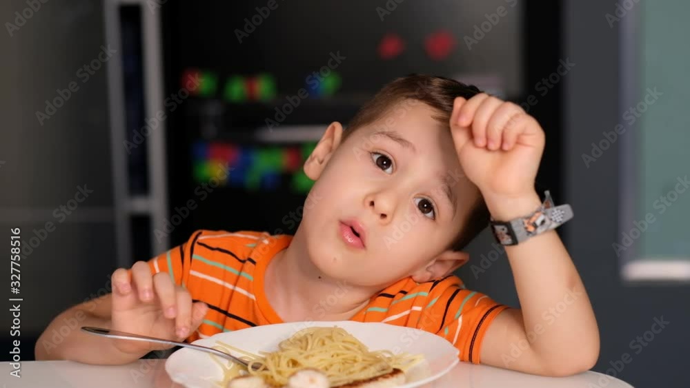 child playing with pasta at dining table. messy face eating. sauce and ...
