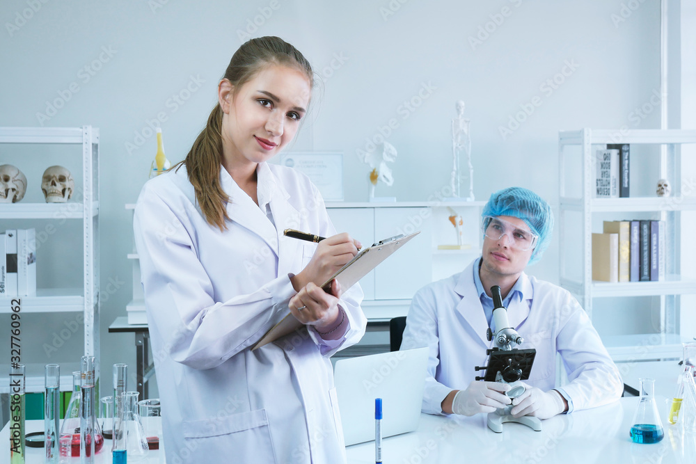 Female Research Scientist write a short note and working in laboratory ...