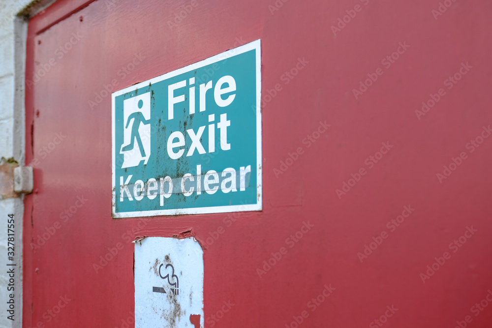 Shallow focus of an old Fire Exit and No Smoking sign seen attached for ...