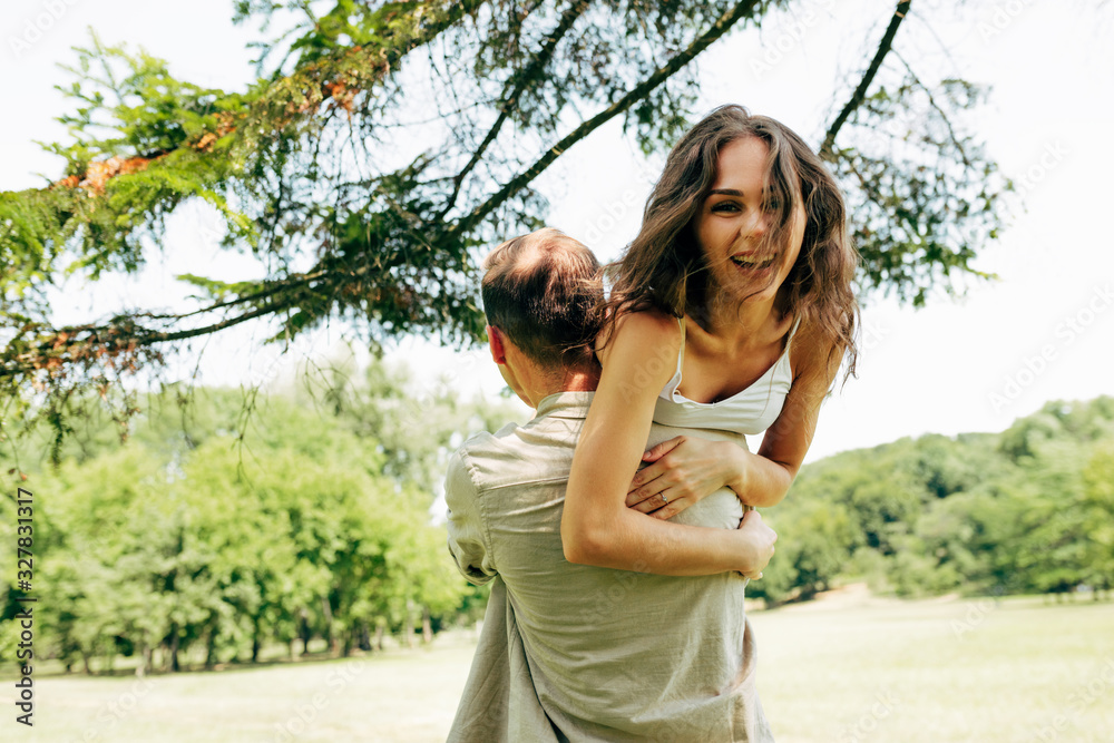 Handsome young man carrying his beautiful smiling woman on his back at ...