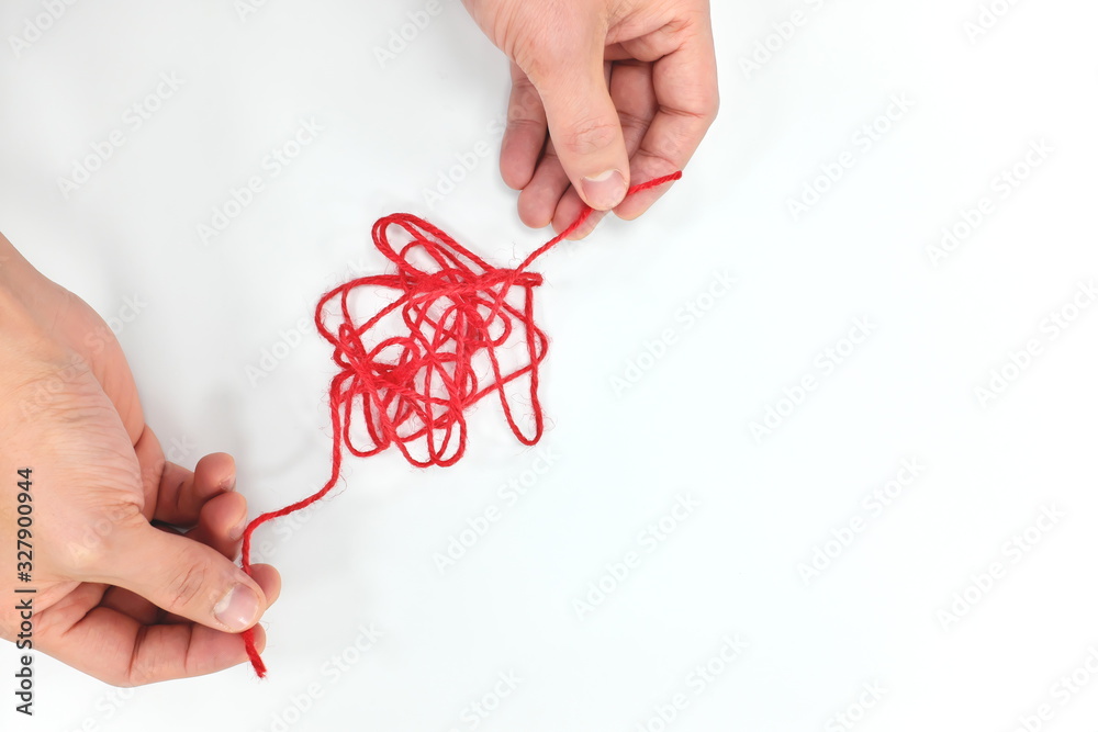 Hands fixing a tangled red yarn in white background. Problem solving ...