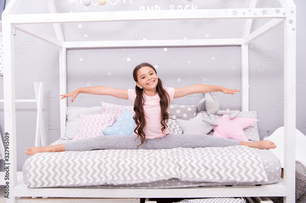 Adorable gymnast. Happy child sit in split position. Little girl do ...