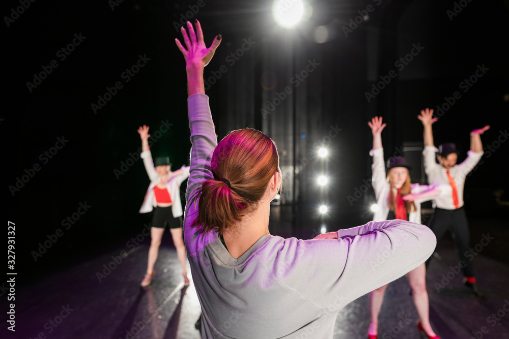 Female dance instructor guiding jazz dancers on stage Stock Photo ...