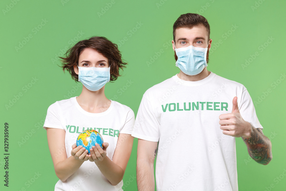 Two friends couple in volunteer t-shirt isolated on pastel green ...