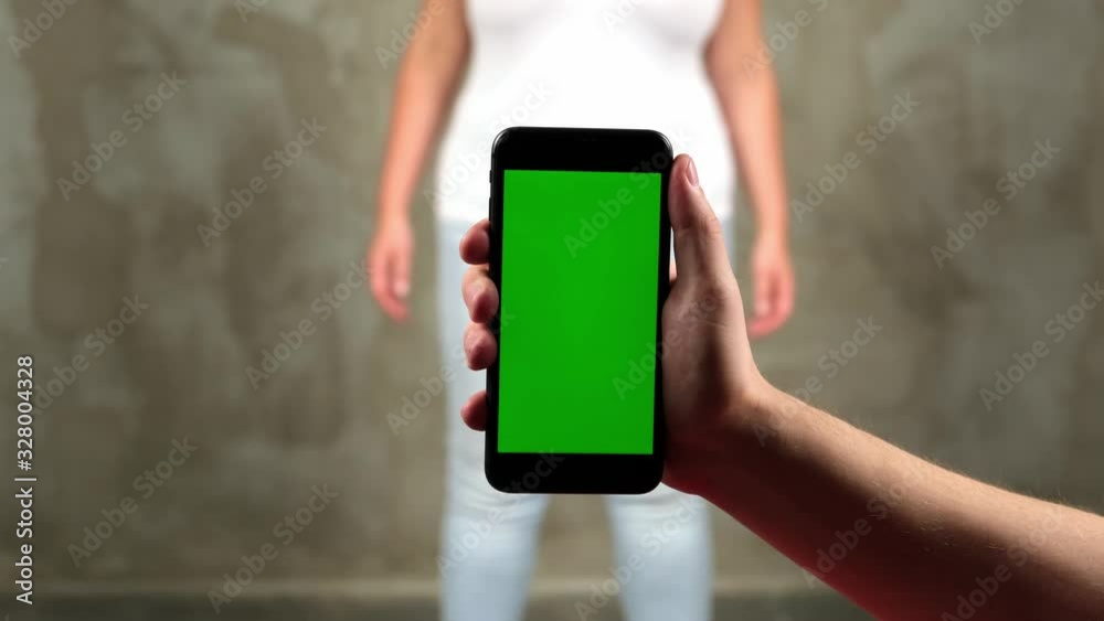 man's hand holding a mobile telephone with a vertical green screen in tram chroma key smartphone ...