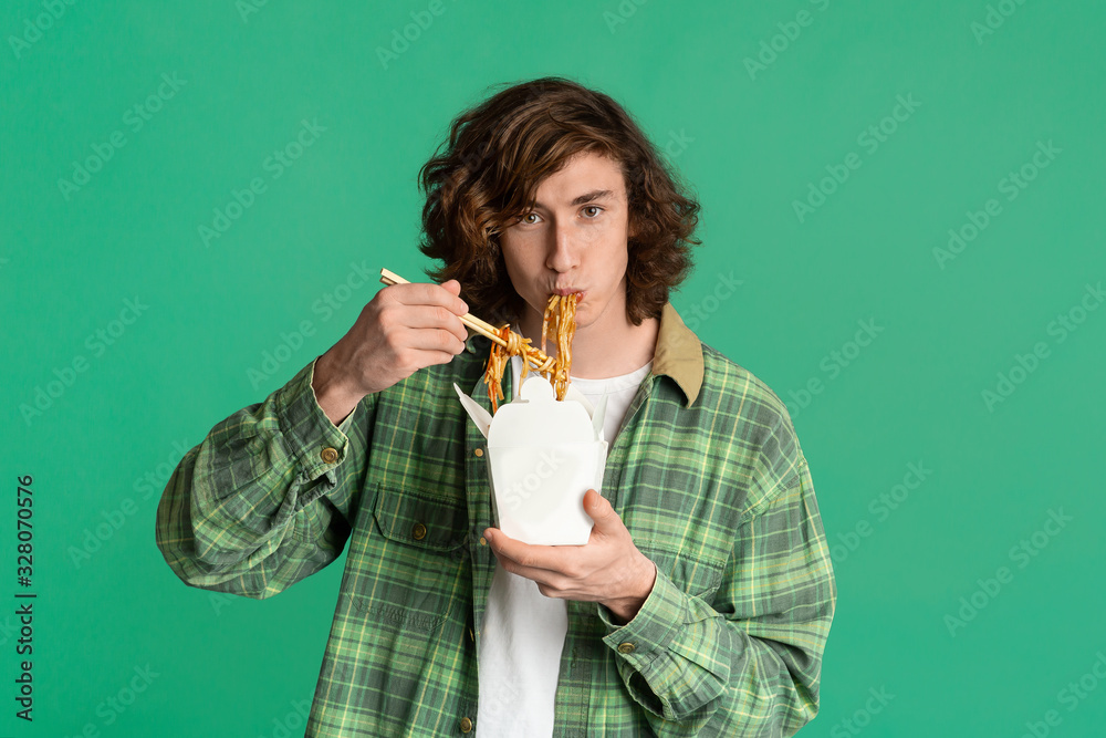 Food delivery concept. Young man eating takeaway noodles on color ...