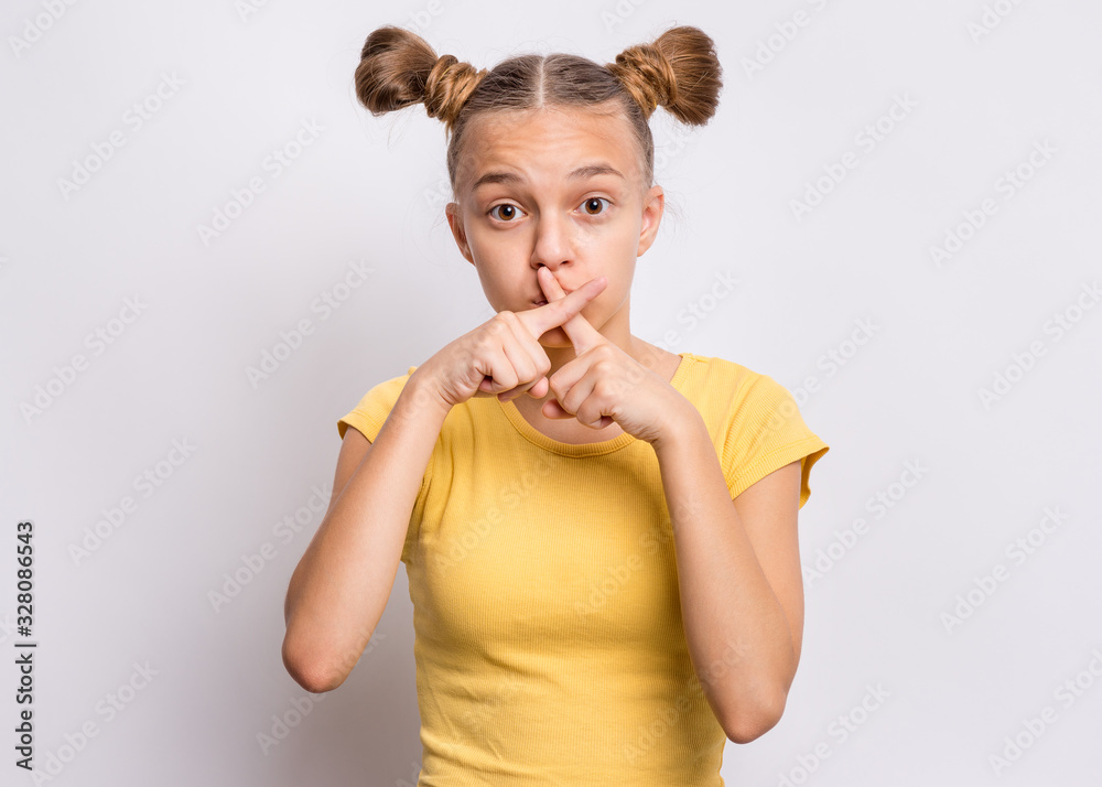 Portrait of teen girl asking to be quiet with fingers on lips, isolated ...