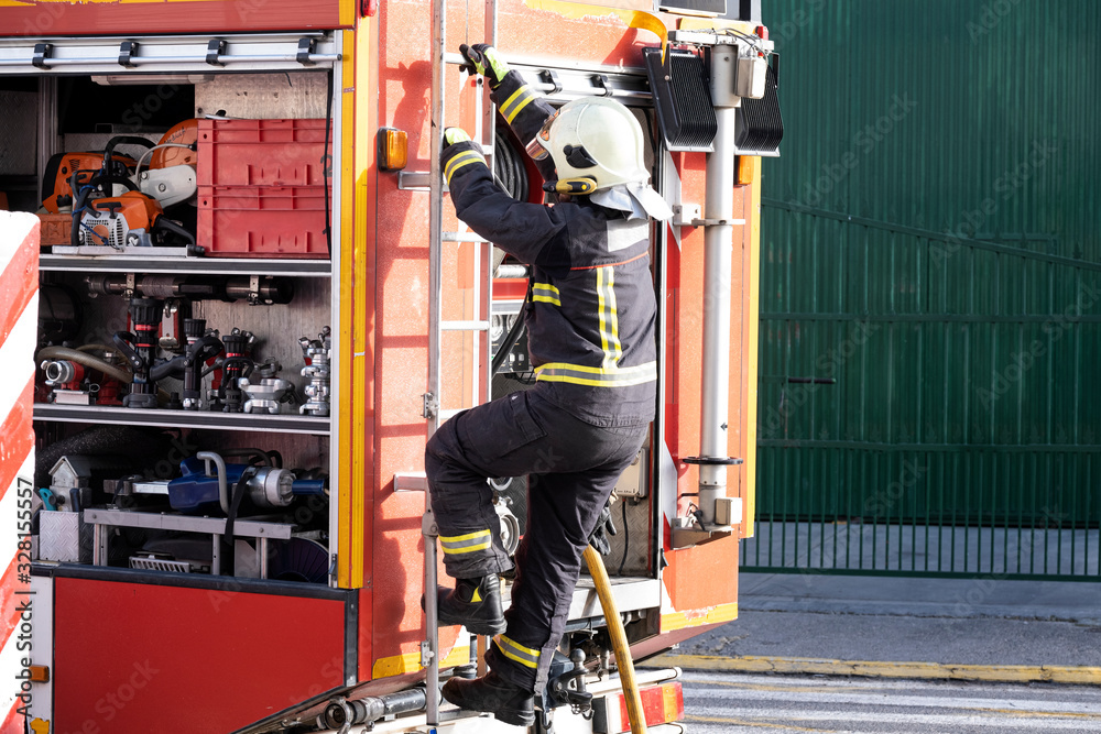 fully equipped fireman climbing the ladder of a fire truck Stock Photo ...
