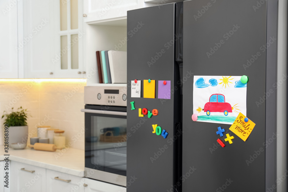 Modern refrigerator with child's drawing, notes and magnets in kitchen ...