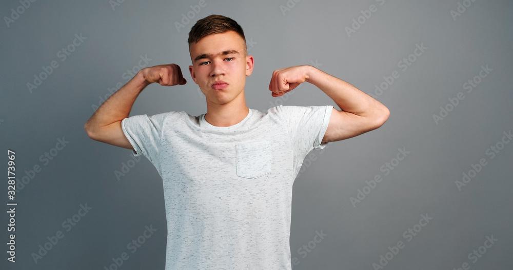 Portrait of confident sports teenager boy showing her biceps triceps ...