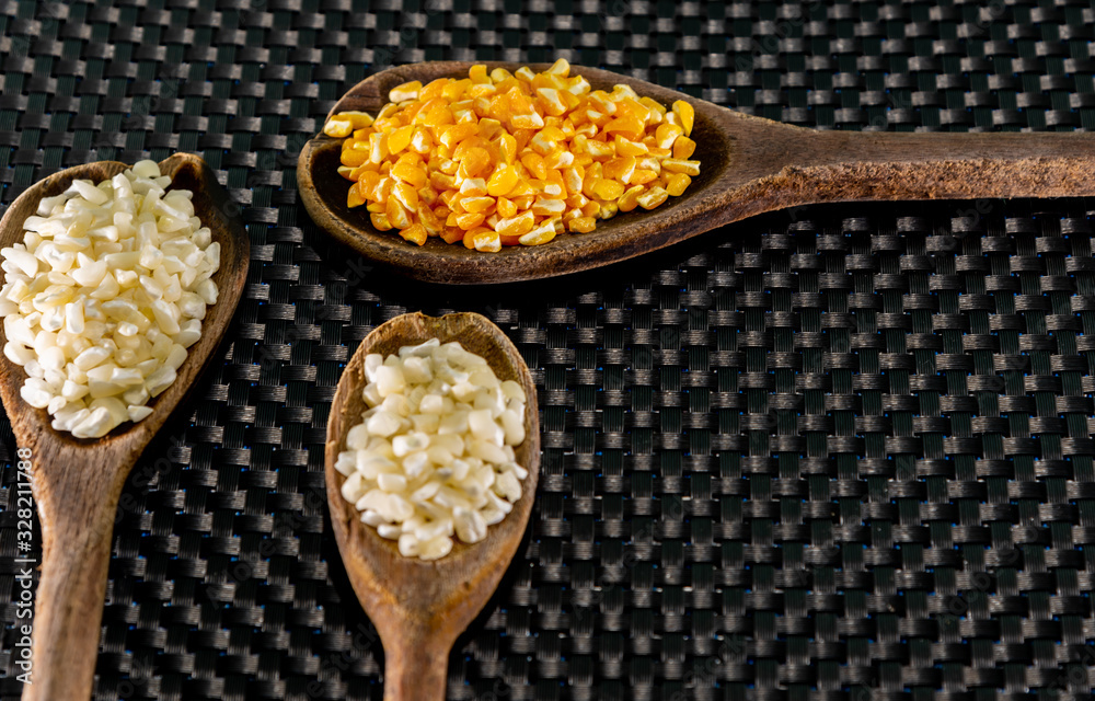 Milho de cor branca e amarela para preparar canjica servida em colheres ...