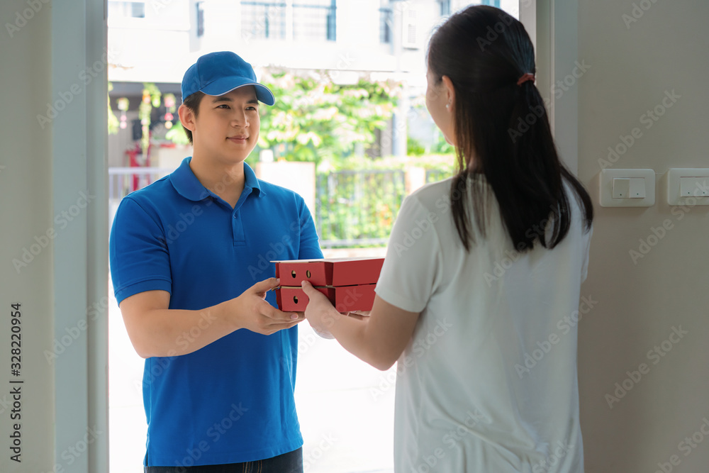 Asian delivery young man in blue uniform smile and holding pizza boxes ...