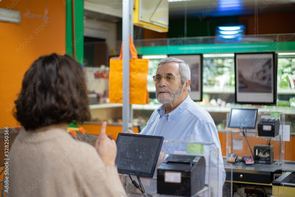 Man and woman talking at pay desk in supermarket. Customer talking with ...
