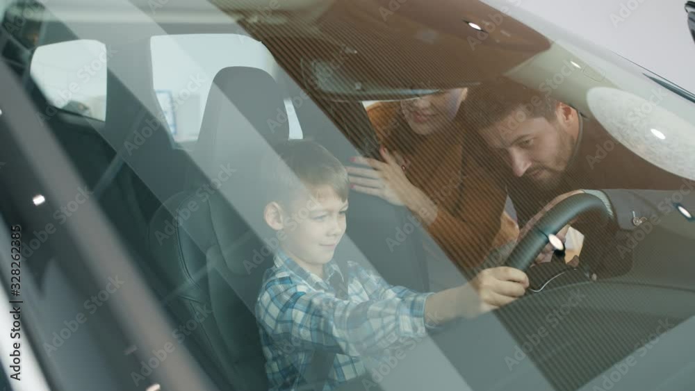 Mother, father and little boy choosing automobile in dealership ...