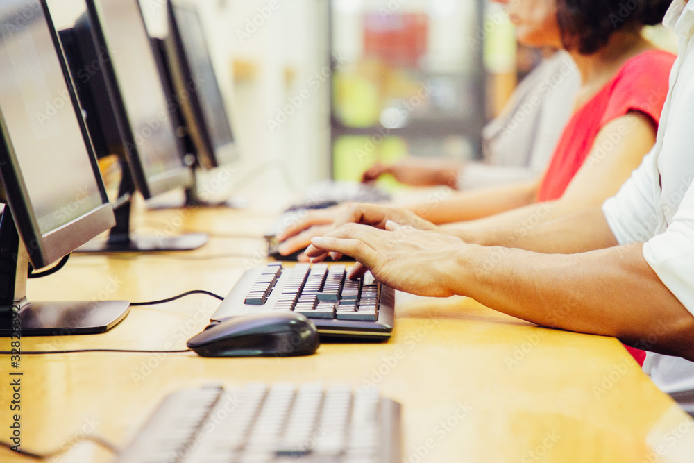 Multiethnic group of students working in computer class. Row of man and women in casual sitting ...