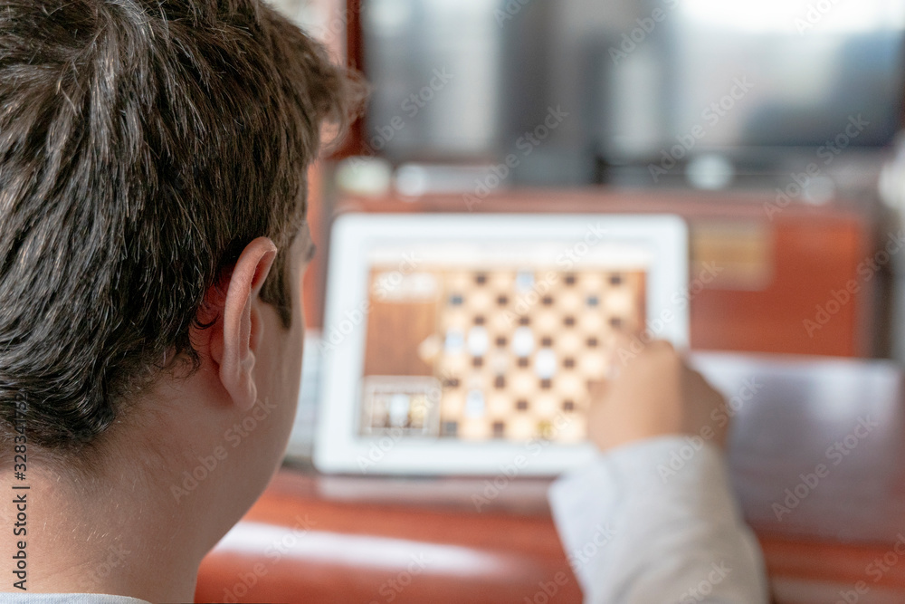 Caucasian boy sitting playing a game of chess on a tablet Stock Photo ...