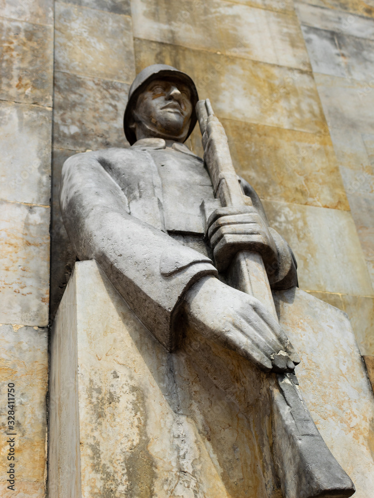 Closed up to an old stone statue of a Soldier holding a rifle in guard ...