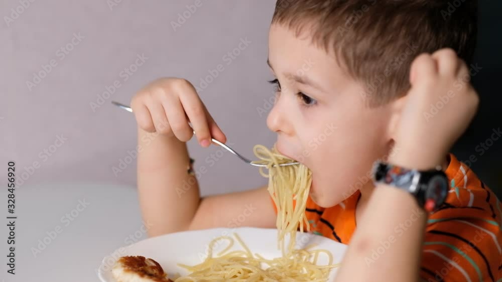 child playing with pasta at dining table. messy face eating. sauce and ...