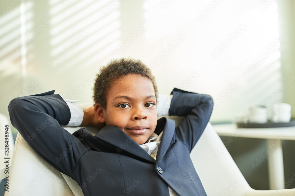 Boy as a manager sits relaxed in a chair Stock Photo | Adobe Stock