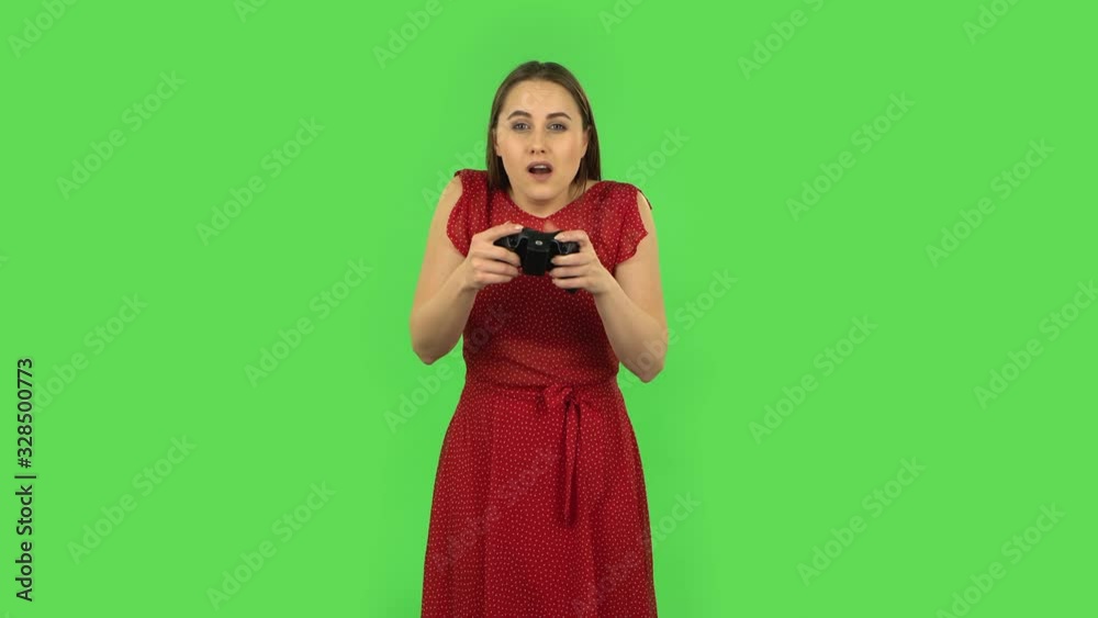 Tender girl in red dress is playing a video game using a wireless ... Tender girl in red dress is playing a video game using a wireless ...