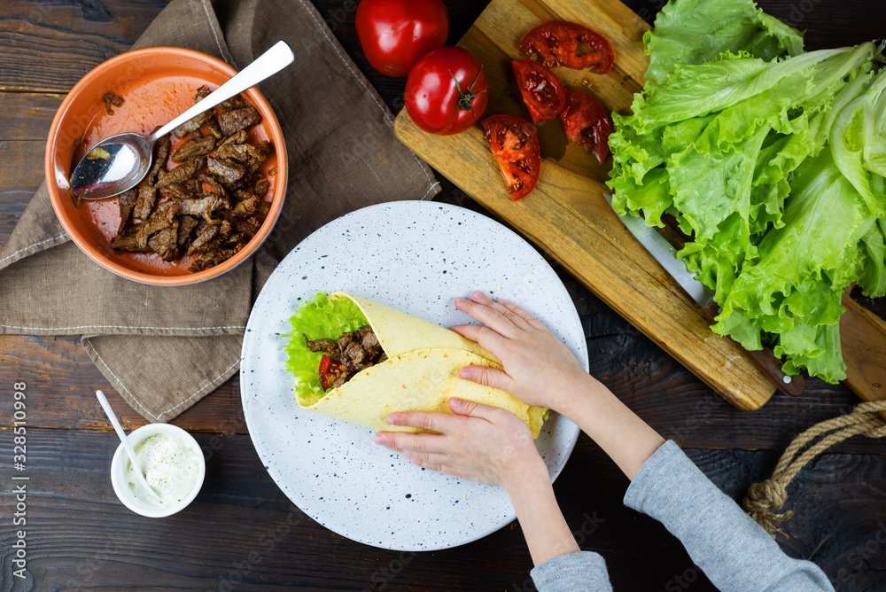 Burrito with slices of fried beef, tomato, lettuce, cheese tortilla ...