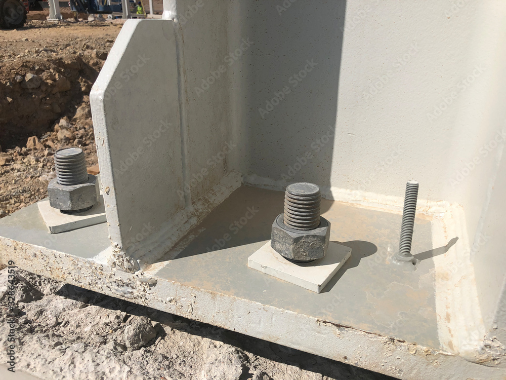 Metal pillar fasten to basement with anchor bolts and nuts. Supporting ...