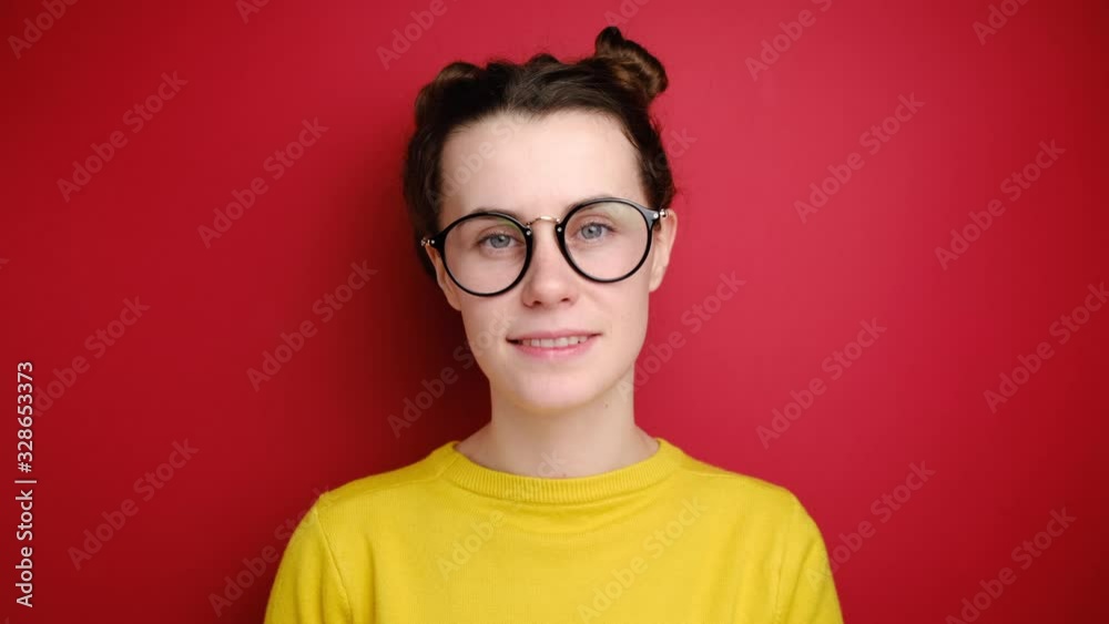 Passionate good looking woman in glasses holds palm near folded lips ...