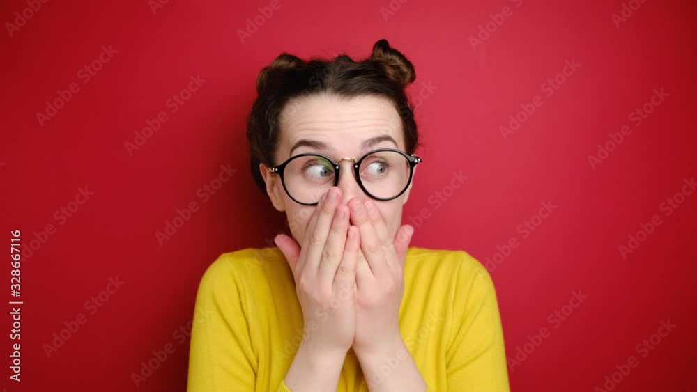 Stupefied woman in glasses looks at camera makes big eyes covering ...