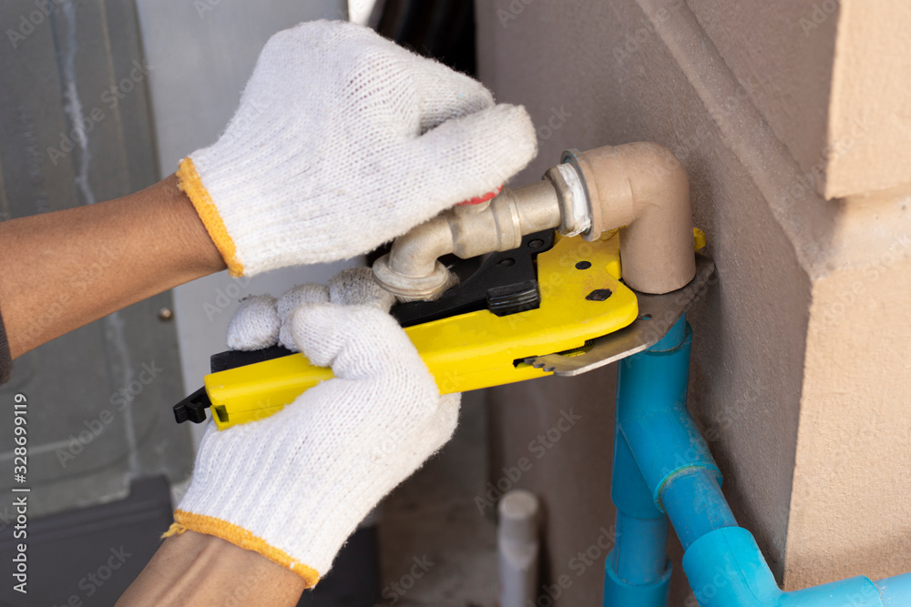 Plumber man hand using pvc pipe cutter for cut the water pipe at home ...