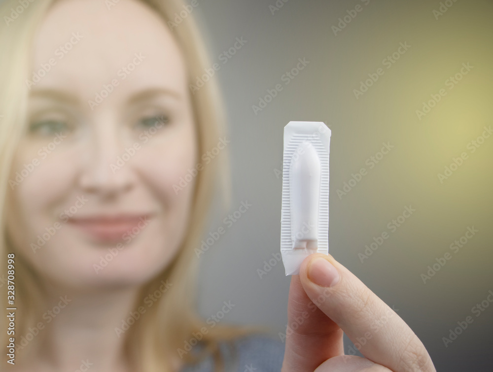 Vaginal or rectal suppository in the hands of a woman. The drug is in ...
