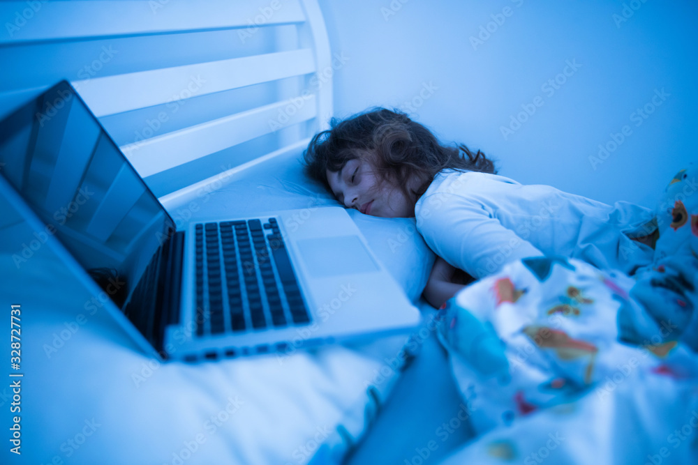 Foto de Small 11 year old girl sleeping next to a laptop - insomnia and ...
