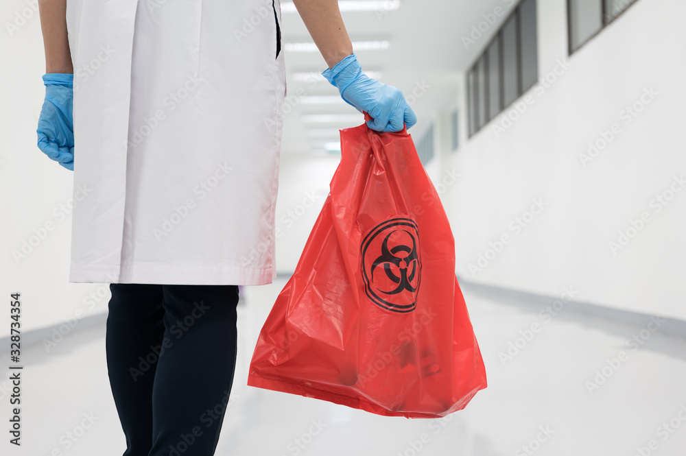 Scientist wearing blue gloves and red bag with bioharzard sign.A woman ...