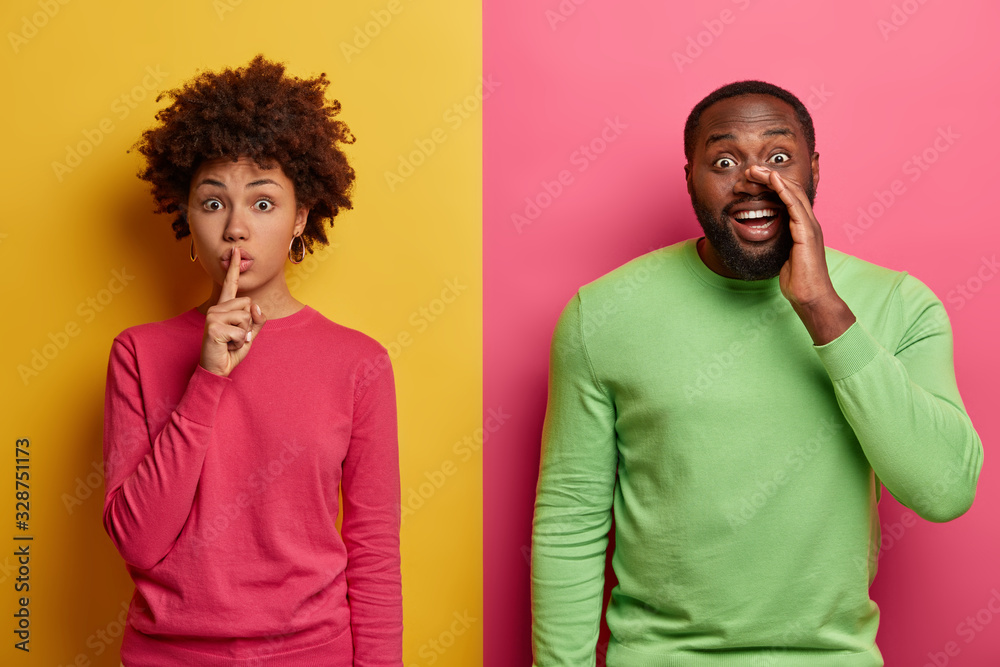 Secret dark skinned young woman and man make silent gesture, whisper ...