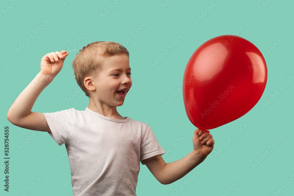 boy in a white t-shirt with a needle in his hand bursts a balloon. a ...