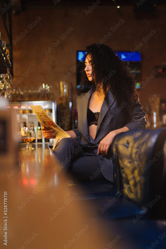 Elegant lady in a business suit, in a restaurant at a bar counter alone ...