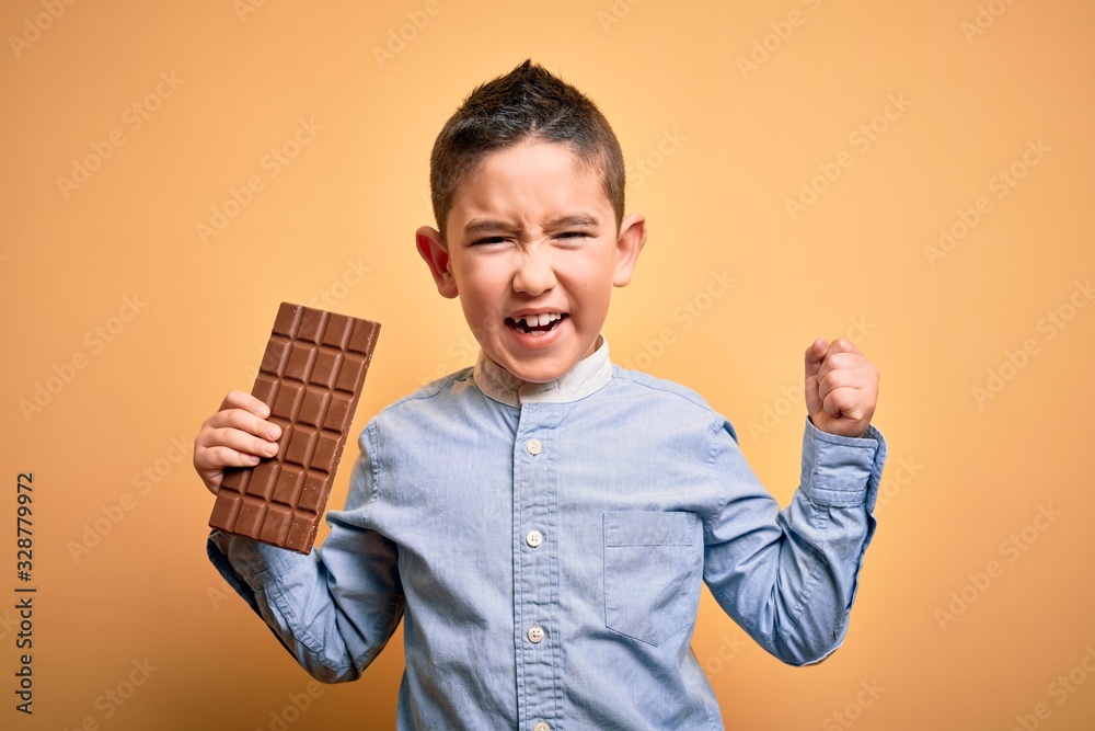 Young little boy kid eating sweet chocolate bar for dessert over ...